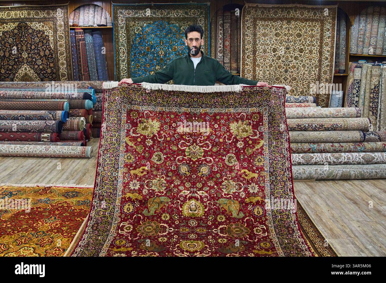 Mohammad Iqbal Bakshi displays a Kashmiri hand-knotted silk carpet at a showroom in Srinagar ...