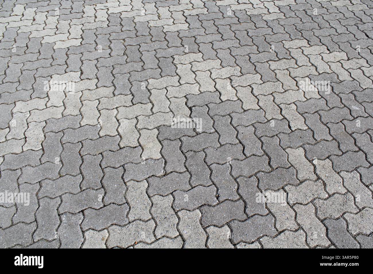 Close up of interlocking grey bricks forming a pattern in a pavement ...