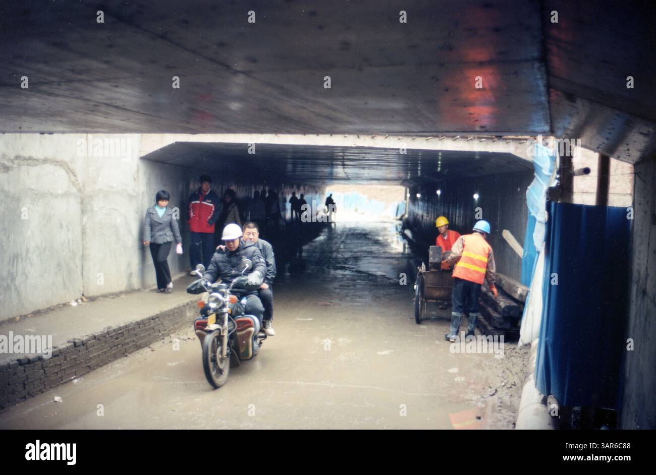 Construction workers and commuters navigate a busy underground tunnel ...