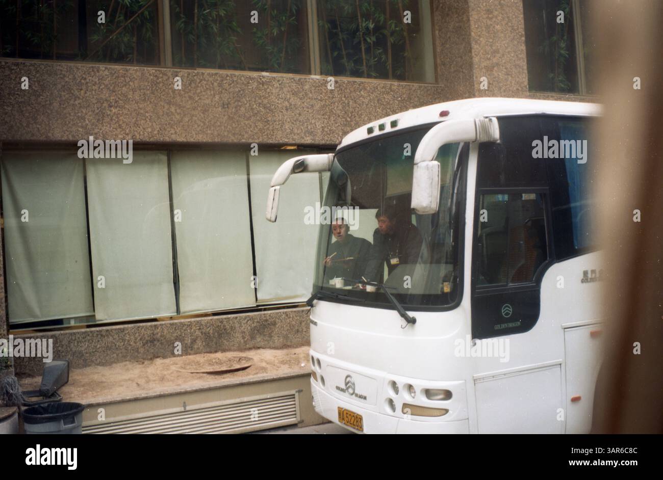 Tour bus waiting outside a modern building with drivers chatting amid ...
