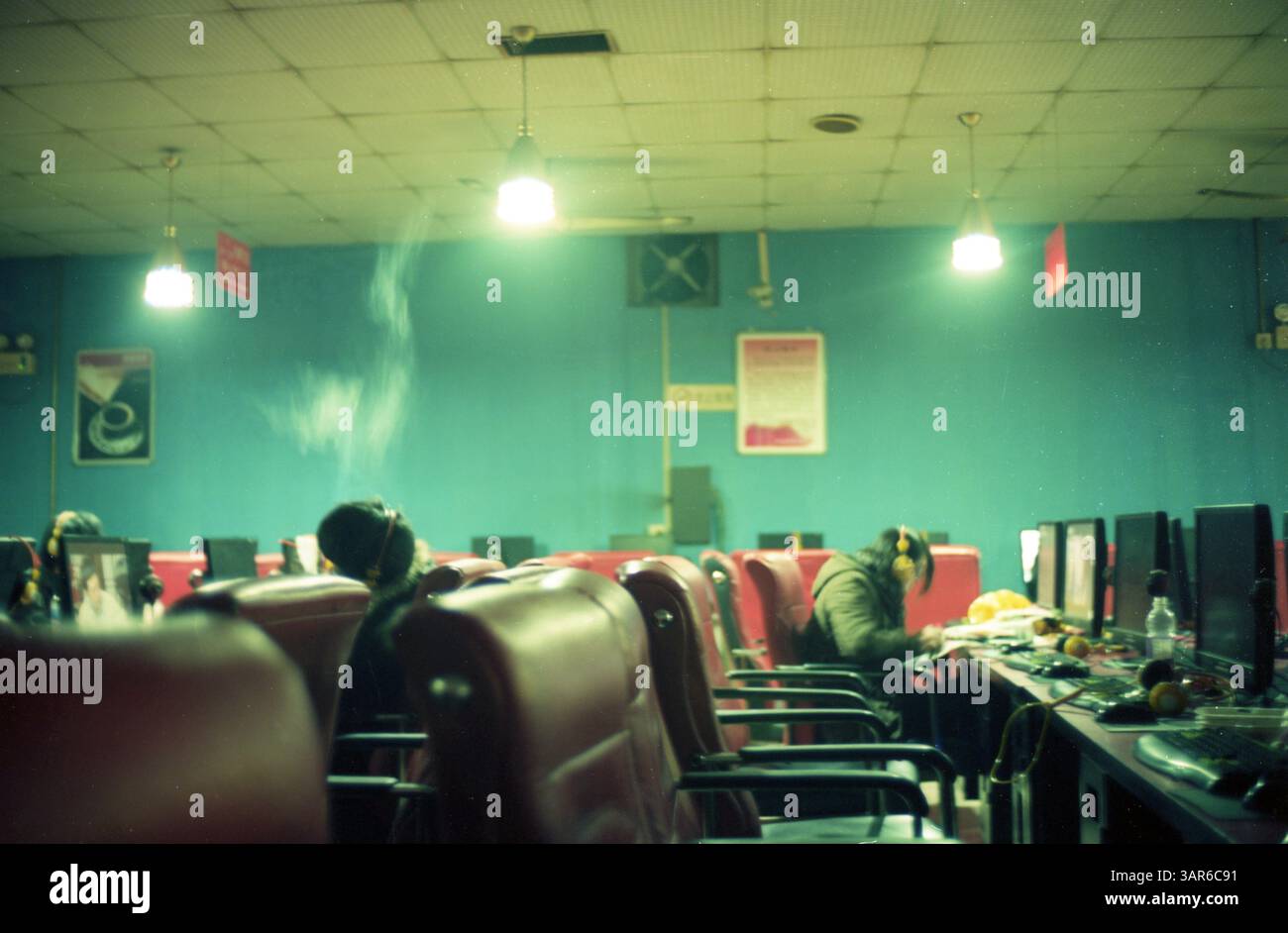 Late night gaming session in a dimly lit internet cafe with focused ...