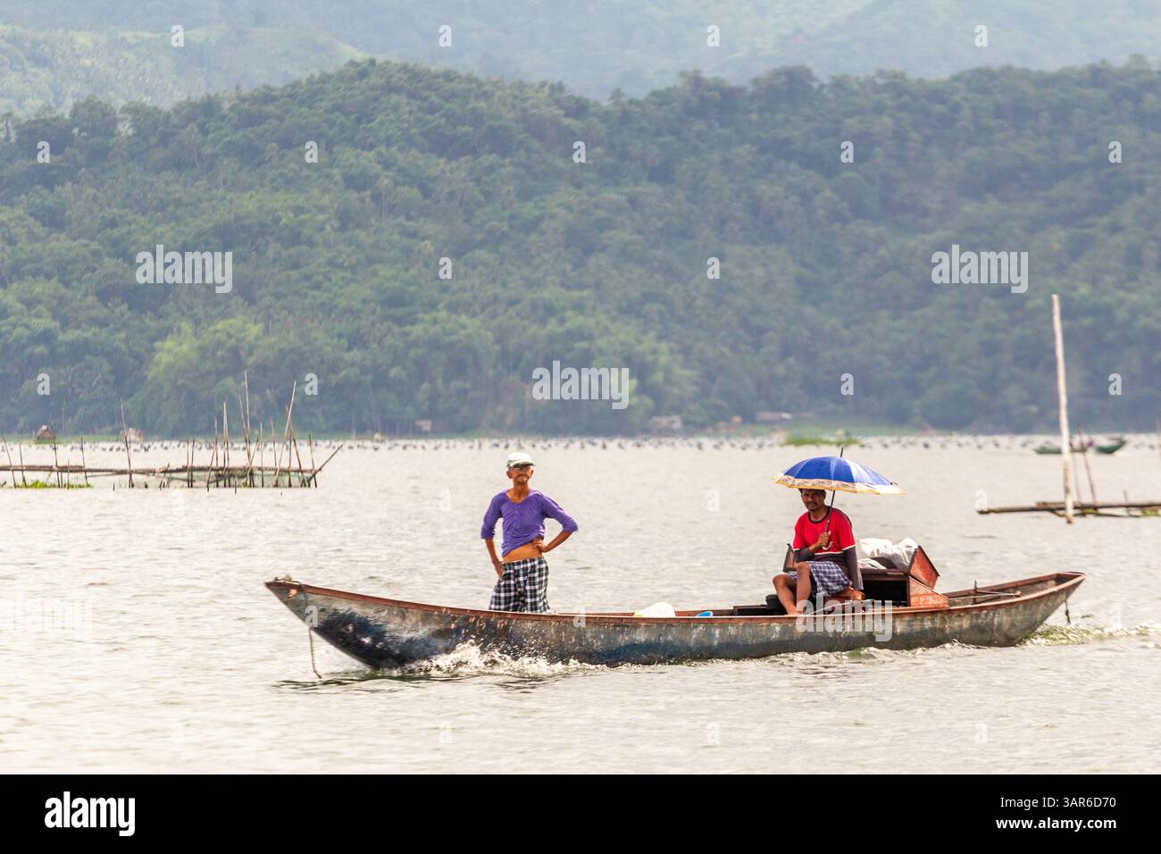 A motorized outrigger boat (banca) carrying a passenger glides across ...