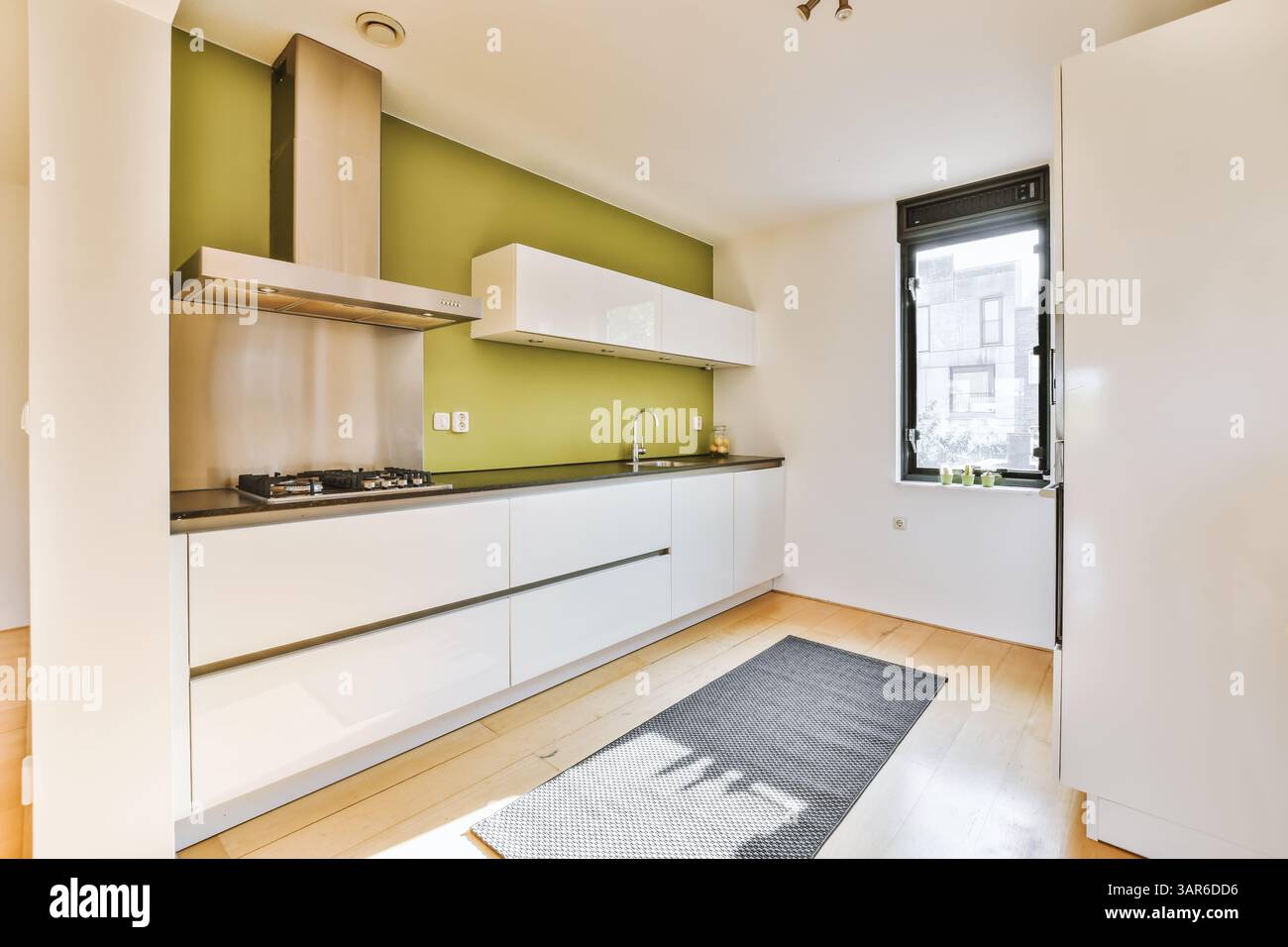 a kitchen area with white cabinets and green accent wall behind the ...