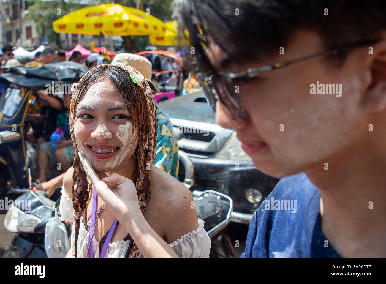 A man is seen gently applying din sor pong (white clay powder) to a ...