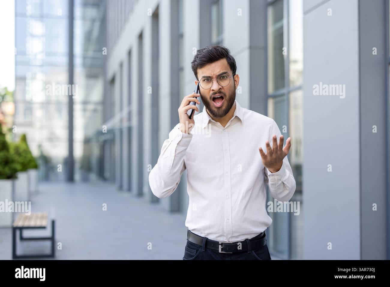 Anxious man is on the phone, expressing frustration with an open mouth ...
