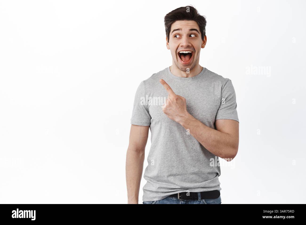 Portrait of excited caucasian male model pointing aside and scream from ...