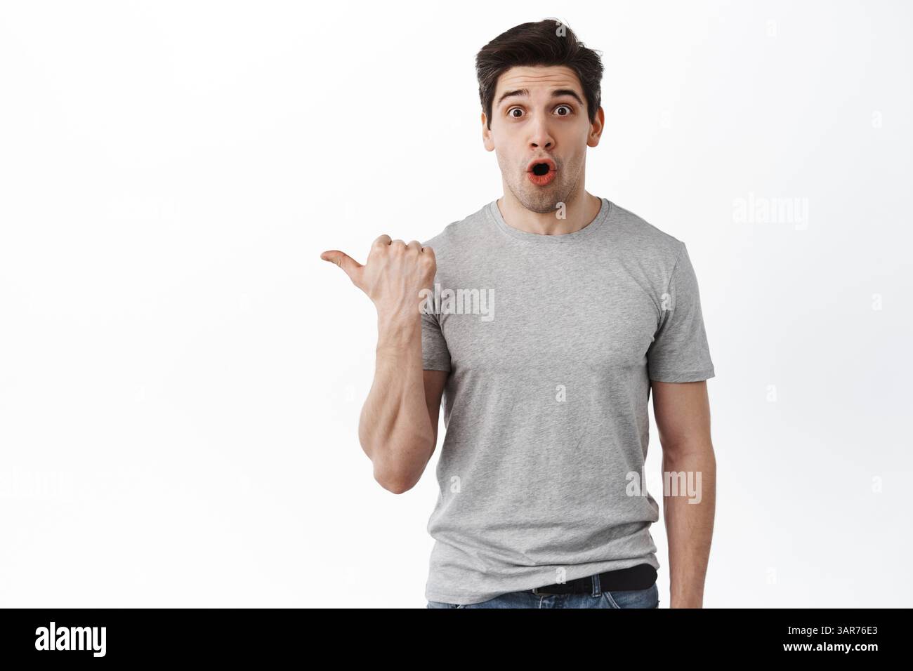 Portrait of surprised 30s man pointing left aside, showing banner with ...