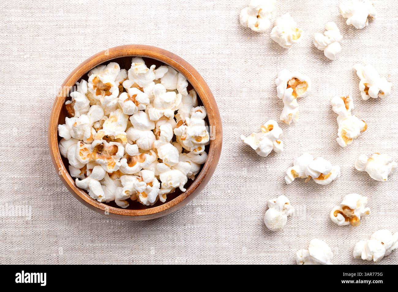 Popcorn, popped corn in a wooden bowl on linen fabric. Seeds of the Zea ...