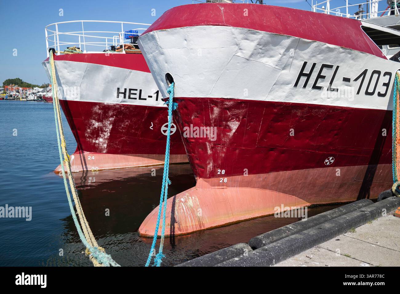 Two boats are docked next to each other, one of which is red and white ...