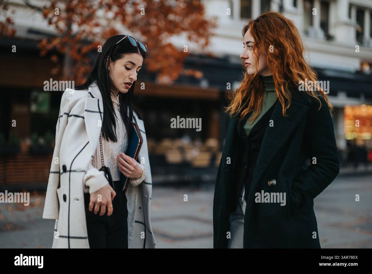 Two Women Conversing Outdoors Amidst a Scenic Urban Setting During Fall ...