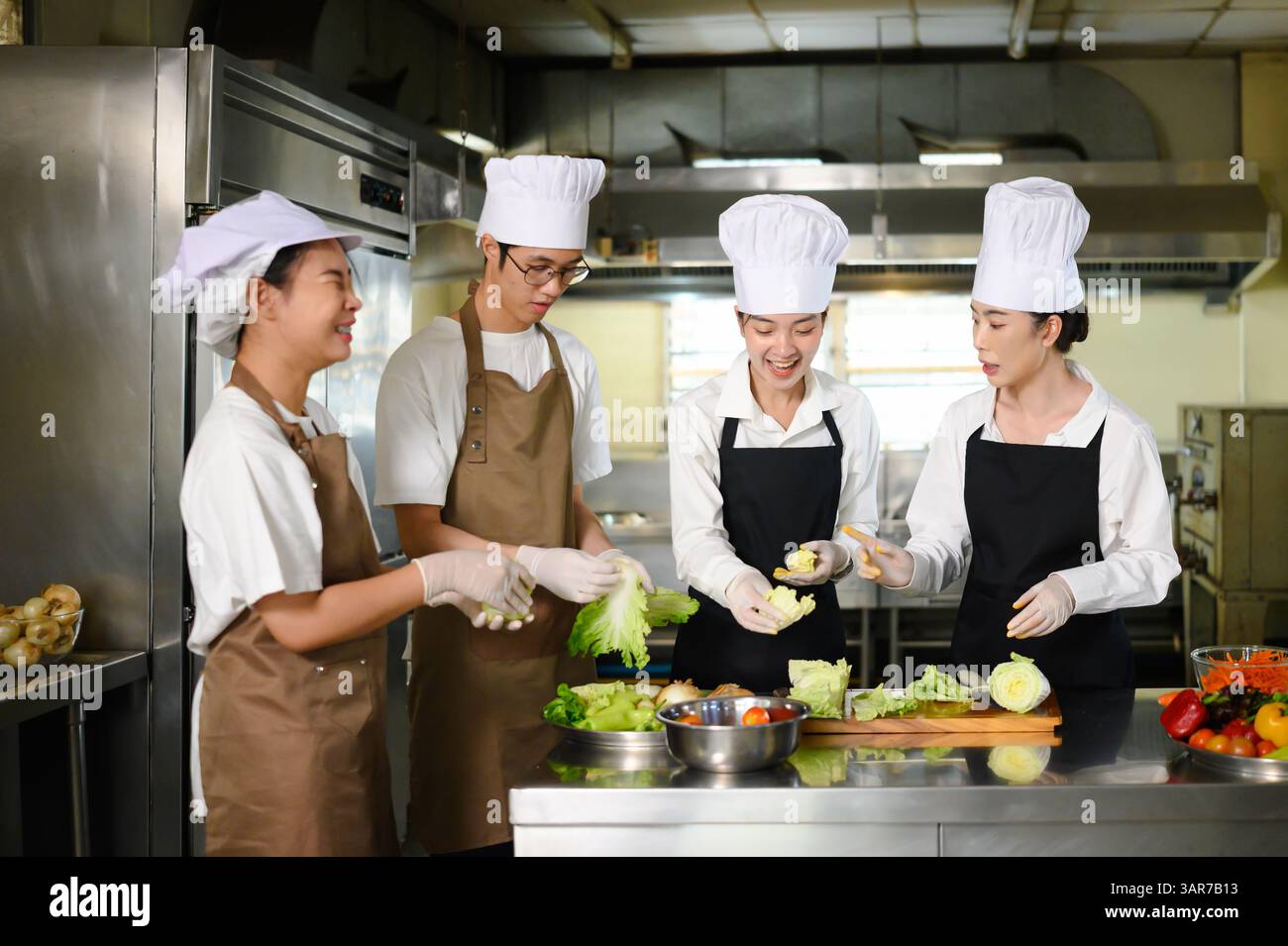 Group of culinary students in chef hats learning food preparation ...