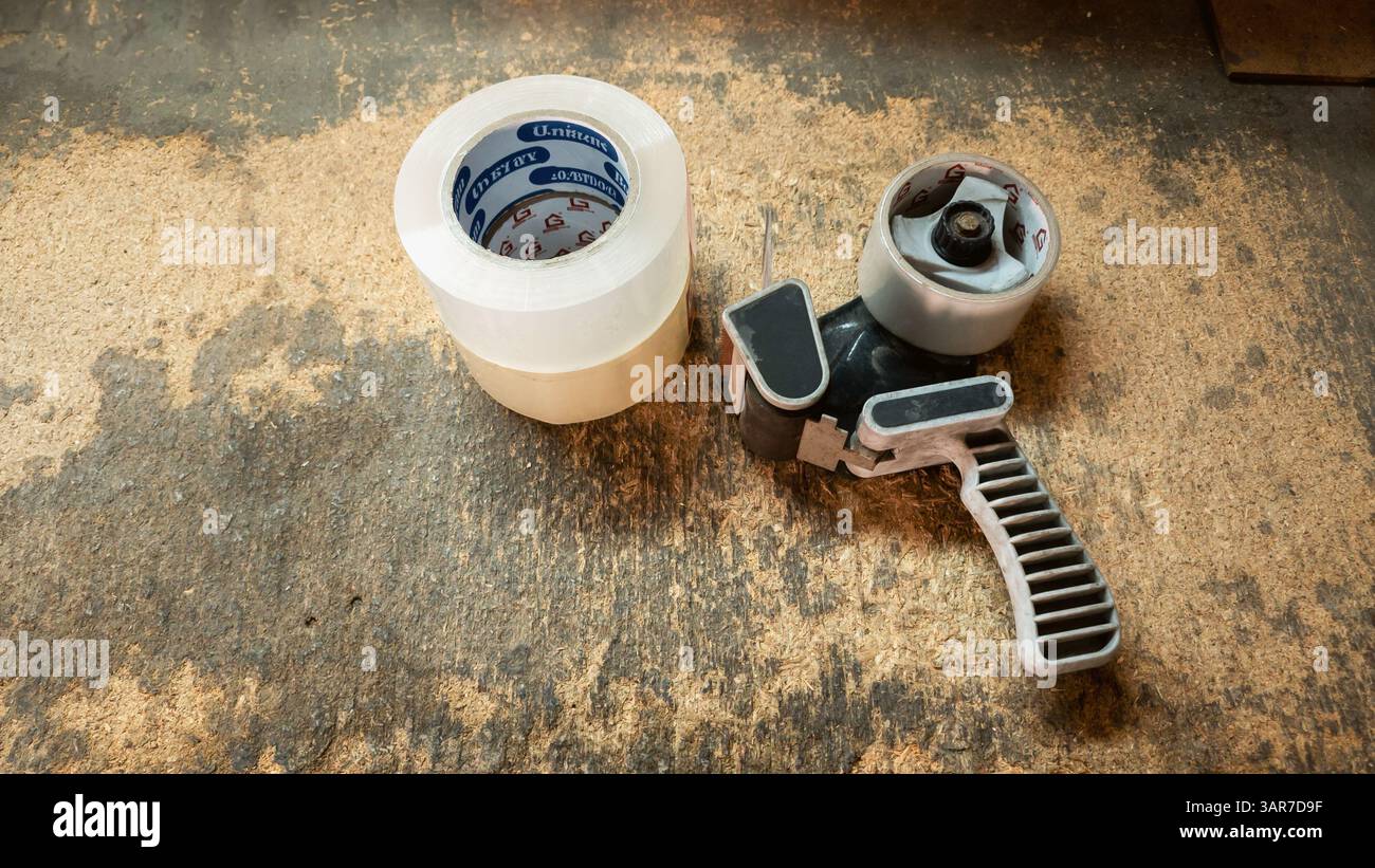 Packing tape dispenser and roll lying on a dusty workbench, ready for ...