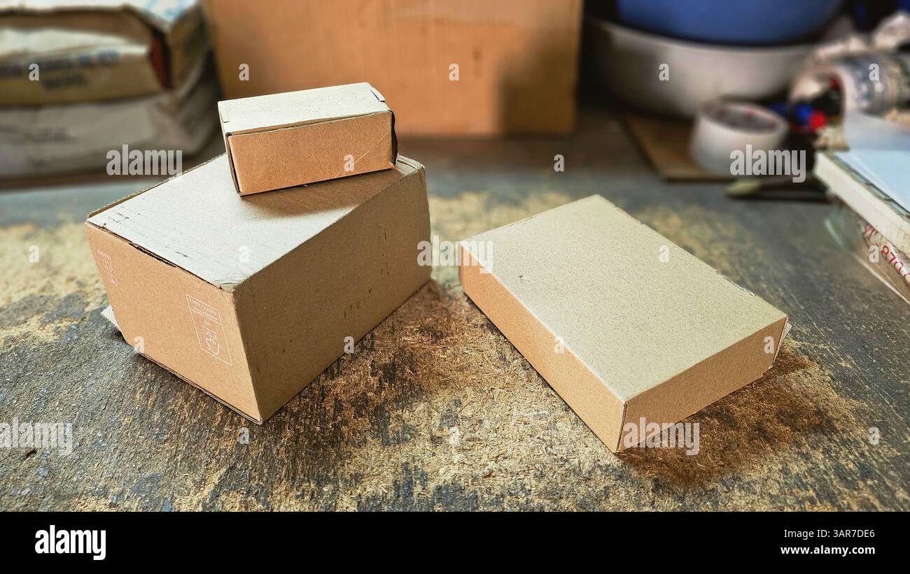 Different sized cardboard boxes sit on a dusty workbench in a warehouse ...