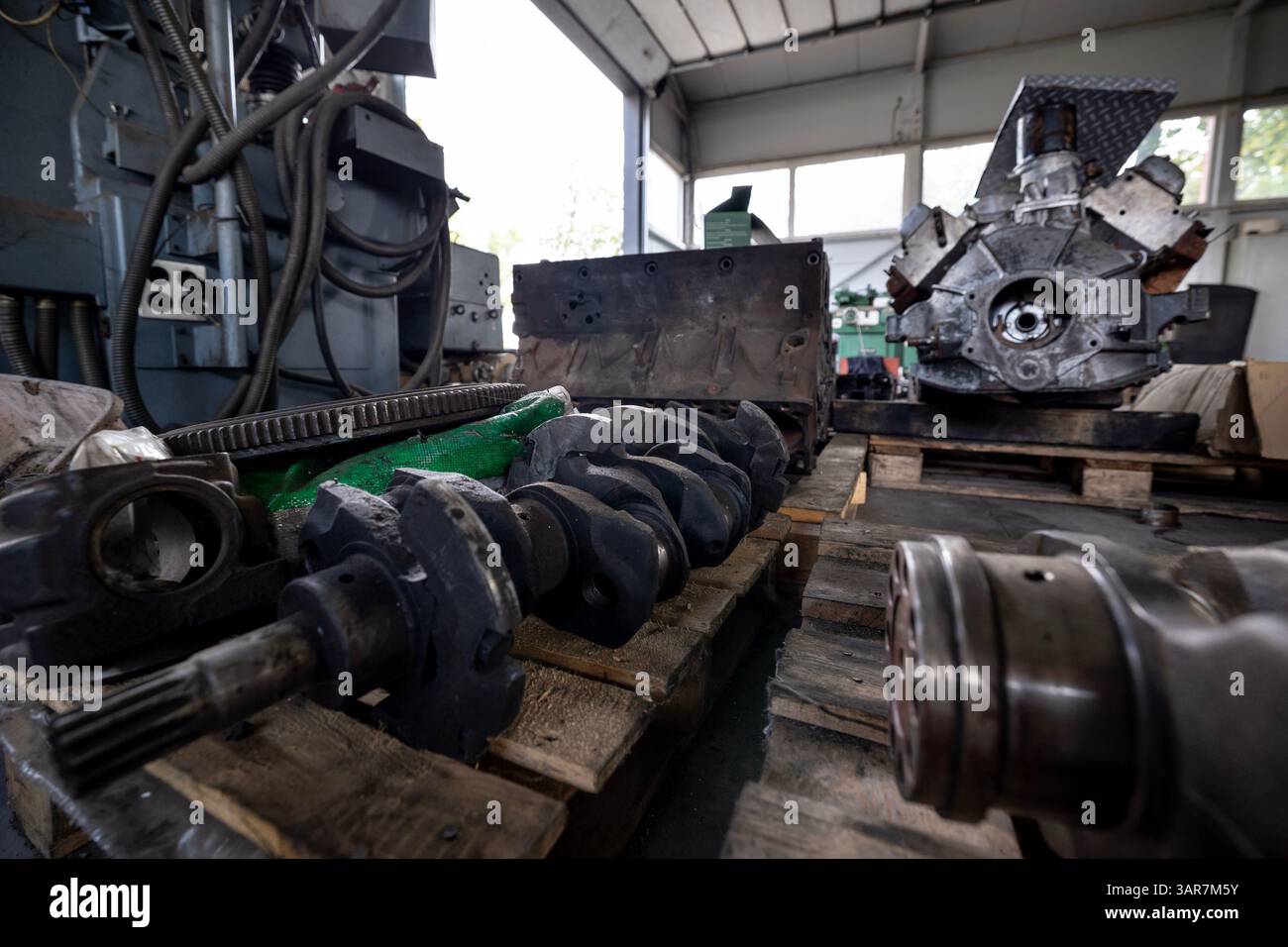 Disassembled engine blocks and crankshafts rest on wooden pallets in a ...