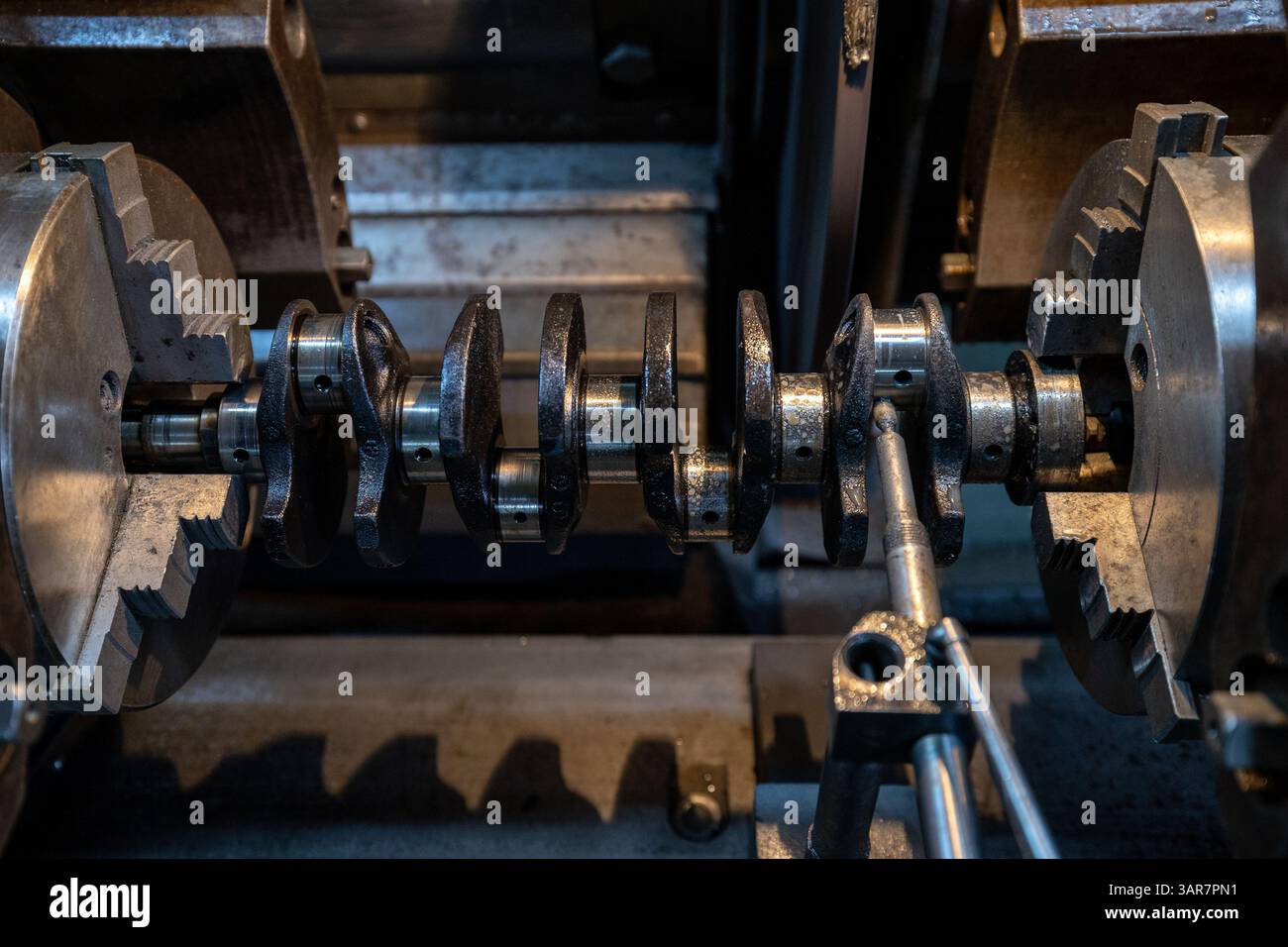 A crankshaft is securely mounted in a grinding machine within a ...