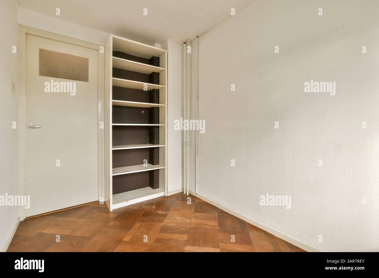 A simple interior space featuring a light-colored wall, wooden flooring ...