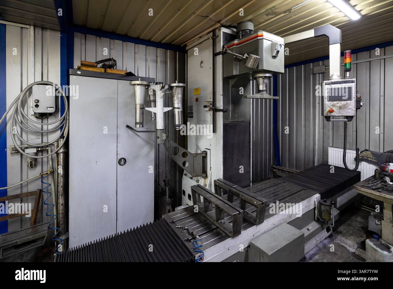 An industrial milling machine is situated within an auto repair shop ...