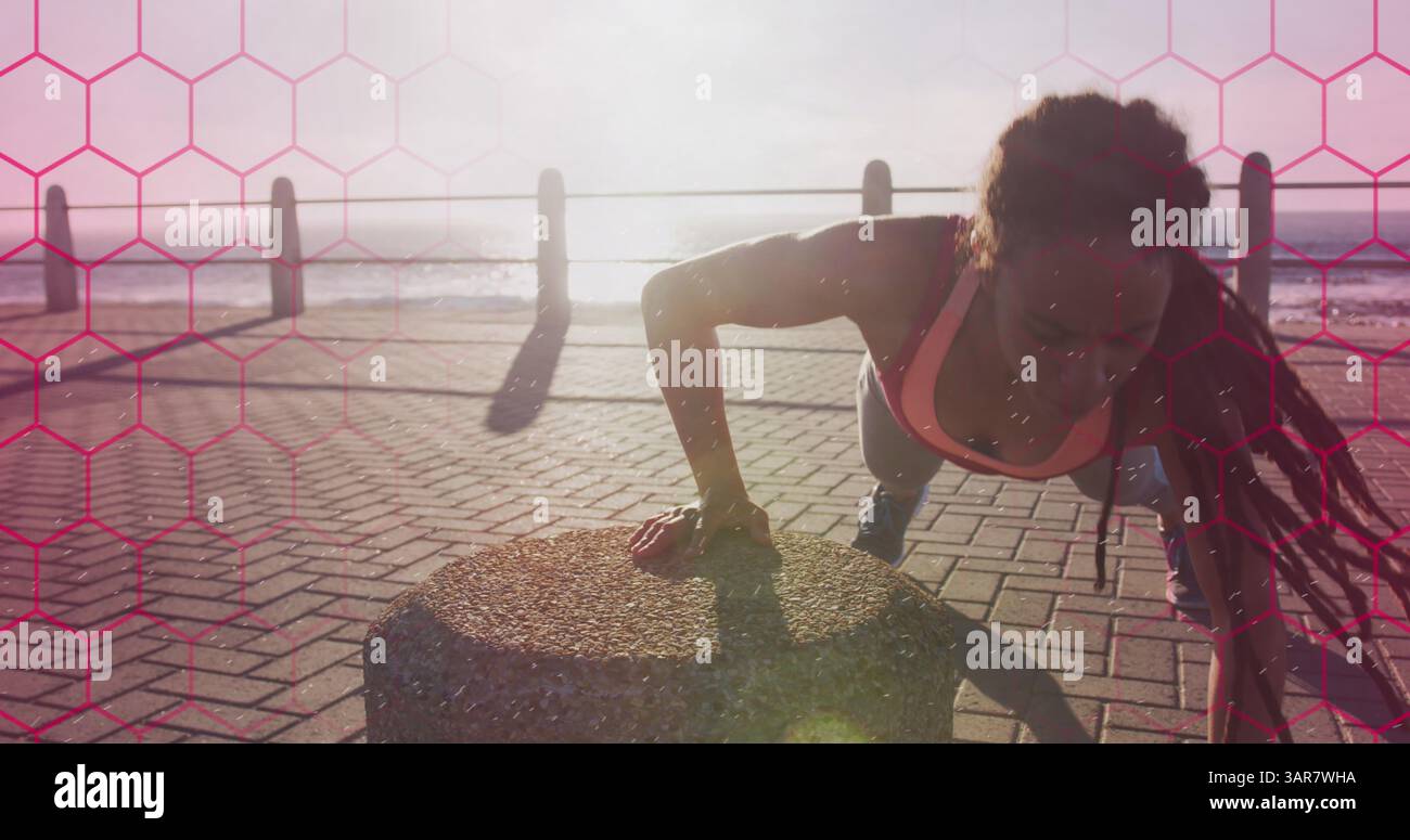 Pink hexagonal shapes against t african american fit woman performing ...