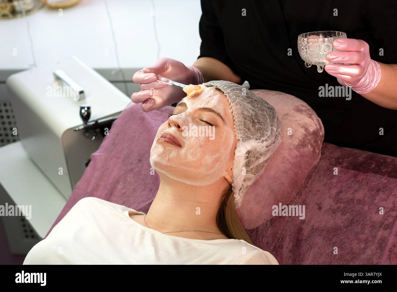Esthetician applies foaming facial mask to client forehead. Facial ...