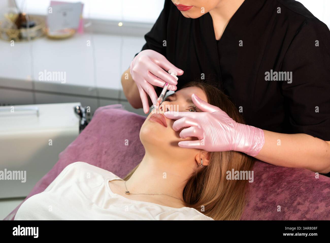 Beauty specialist administers lip filler injection during treatment ...