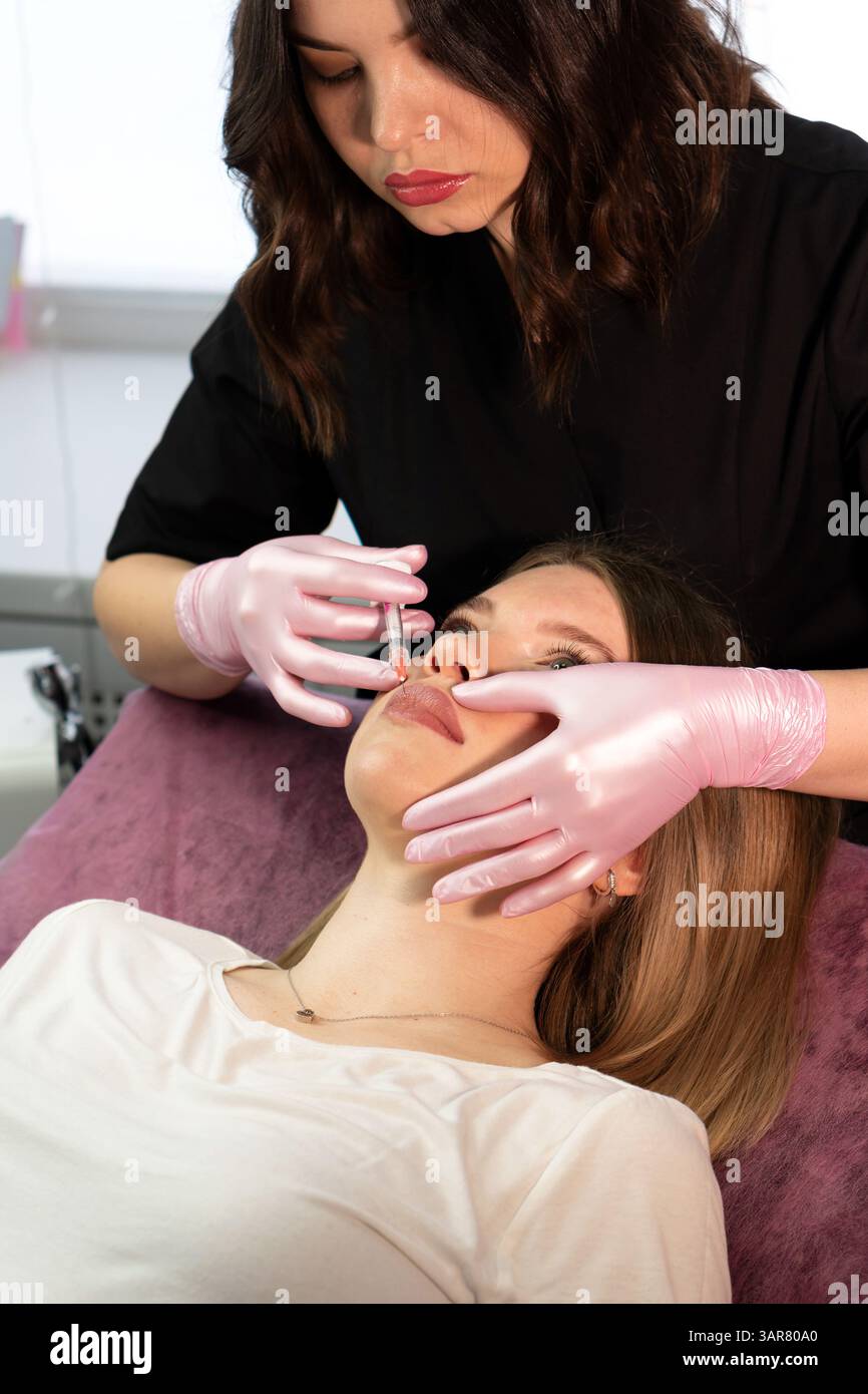 Medical aesthetician performs lip filler injection on patient. Lip ...