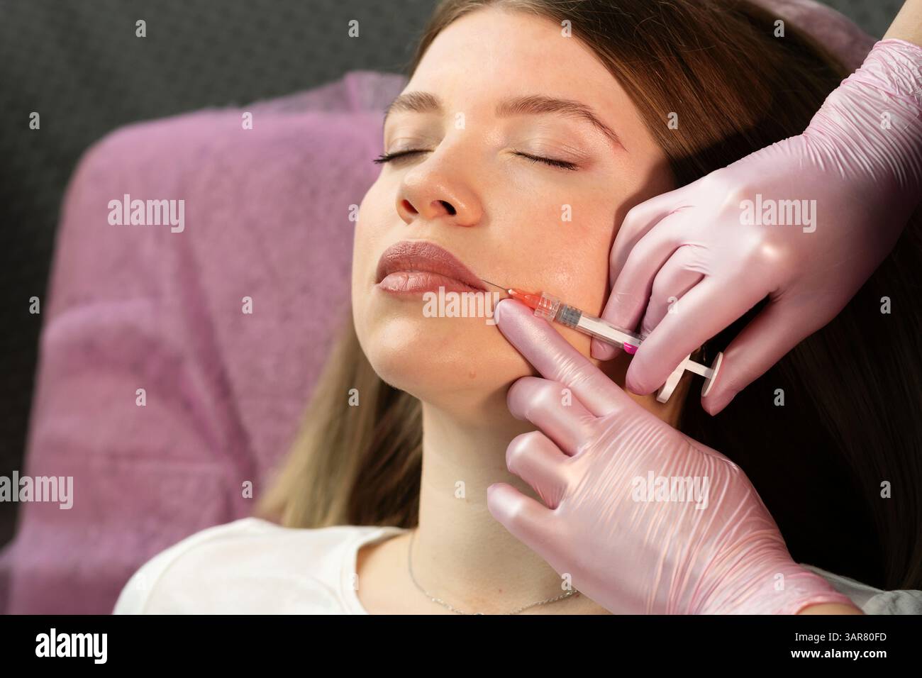 Clinic specialist performs precise lip filler injection on patient. Aesthetic cosmetology. Lip ...