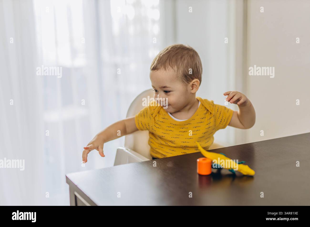 Cute Baby boy sitting in a high chair, playing with mom, capturing a ...