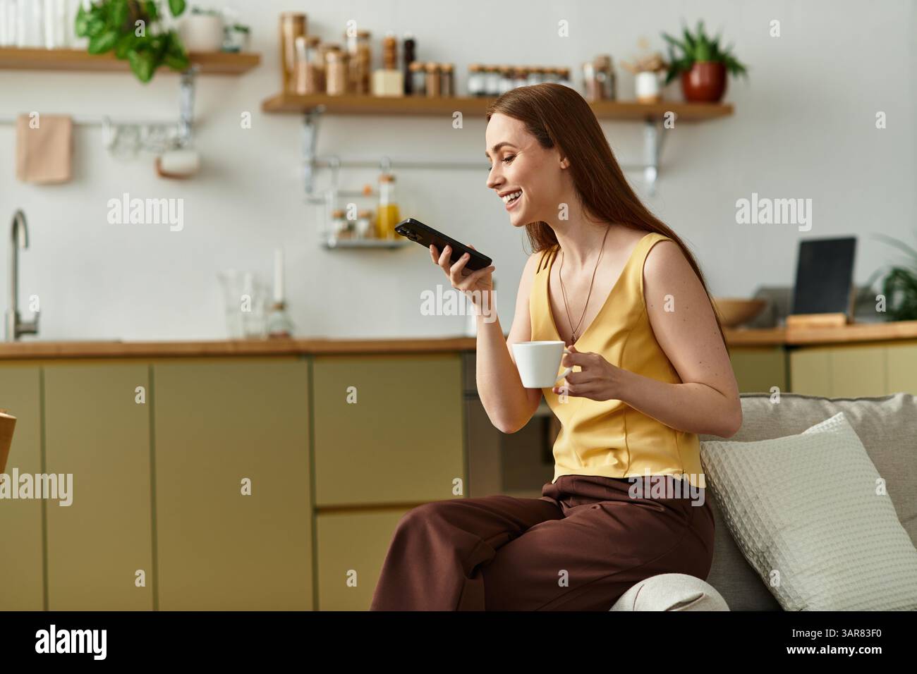A young woman happily chats on the phone while enjoying a warm drink in ...