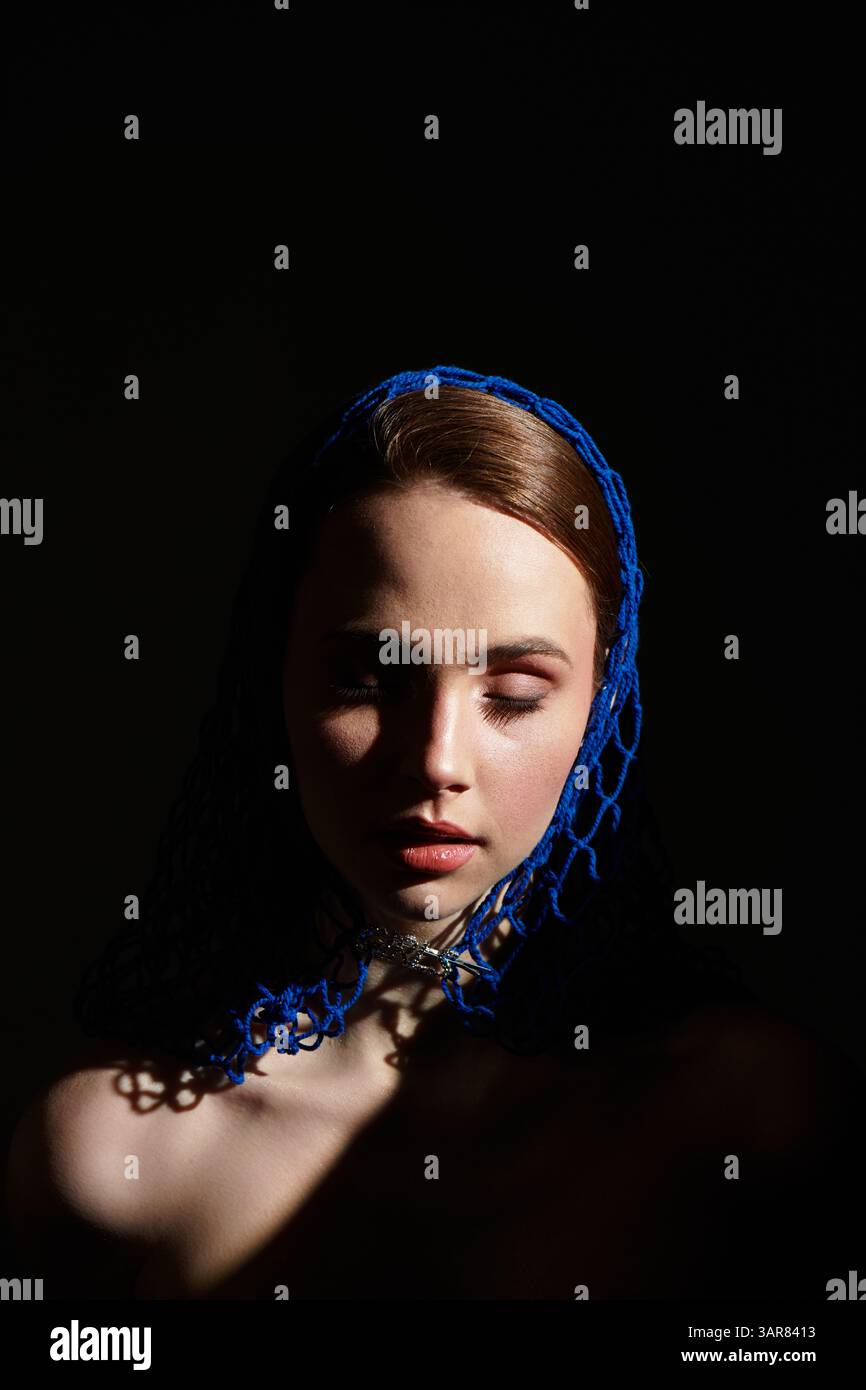 A young woman in a blue headscarf poses gracefully, her serene ...