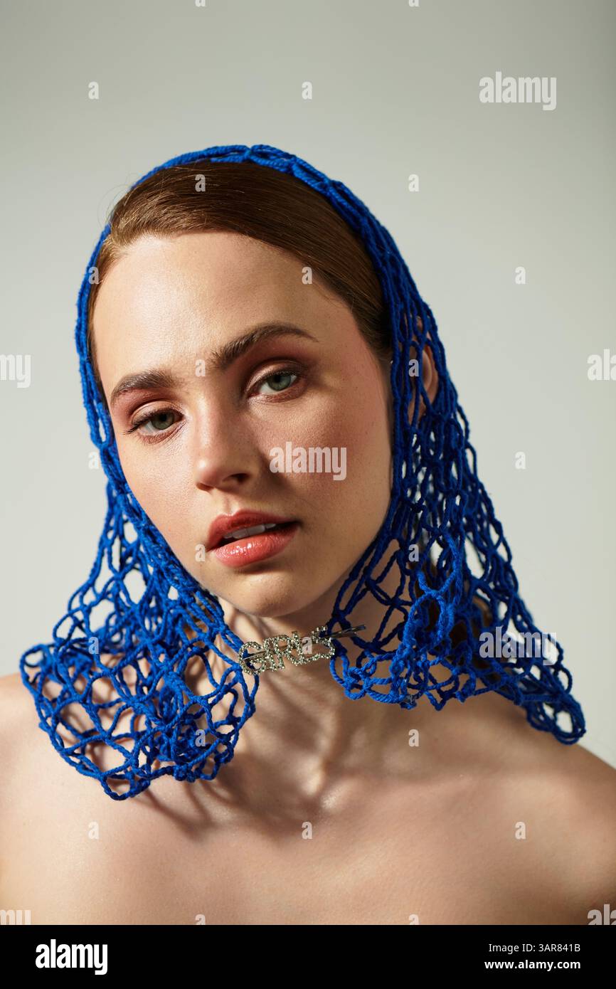 A young woman poses gracefully, draped in a vibrant blue scarf that ...