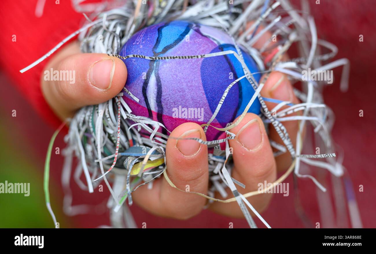 17 April 2025, Thuringia, Weimar: A girl holds a colorfully painted ...