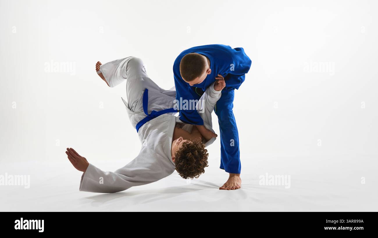 Decisive hip throw unfolding, white gi athlete launches opponent in ...