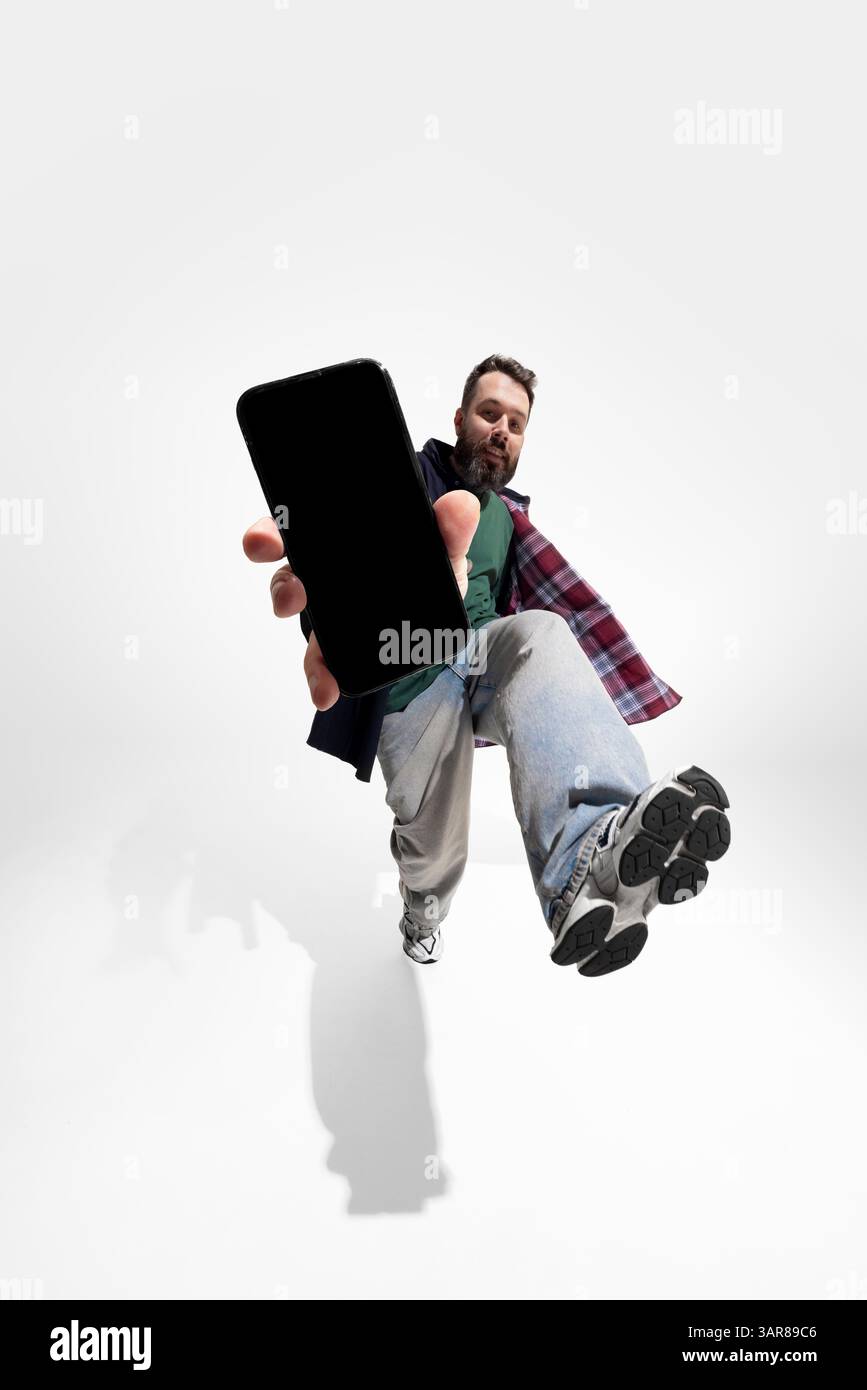 Man in dynamic pose with smartphone with black screen to viewer against ...