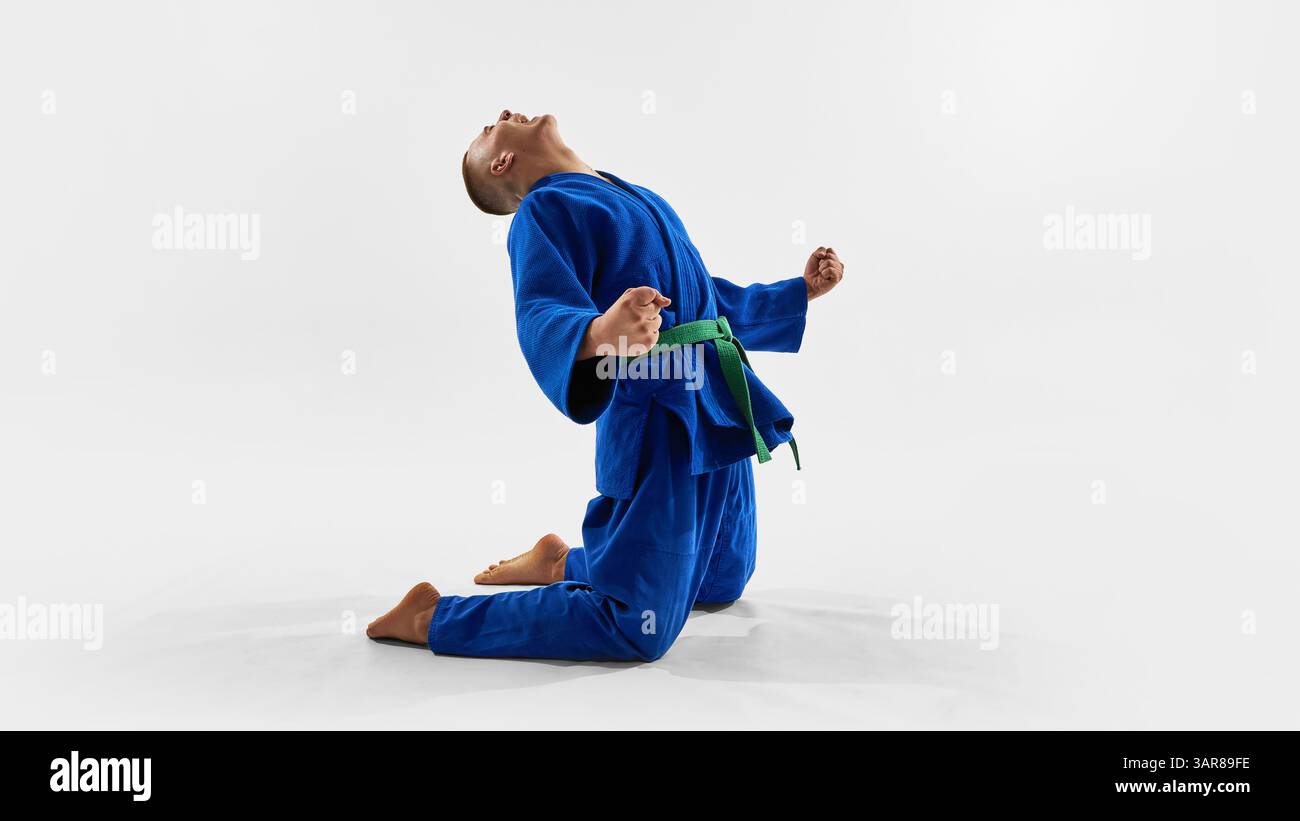 Martial artist celebrates victory on knees, fists clenched, head raised ...