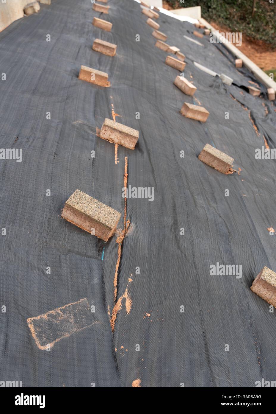 A thick black film covers the ground, preventing grass growth. Bricks ...