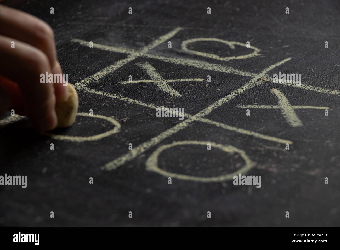 Children's game tic tac toe drawn on a school blackboard and a woman's ...