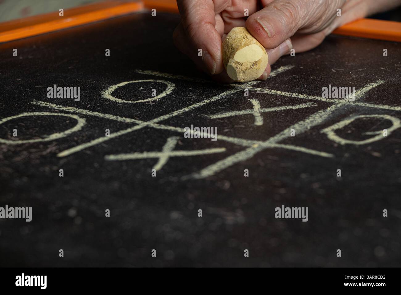 Children's game tic tac toe drawn on a school blackboard and a woman's ...