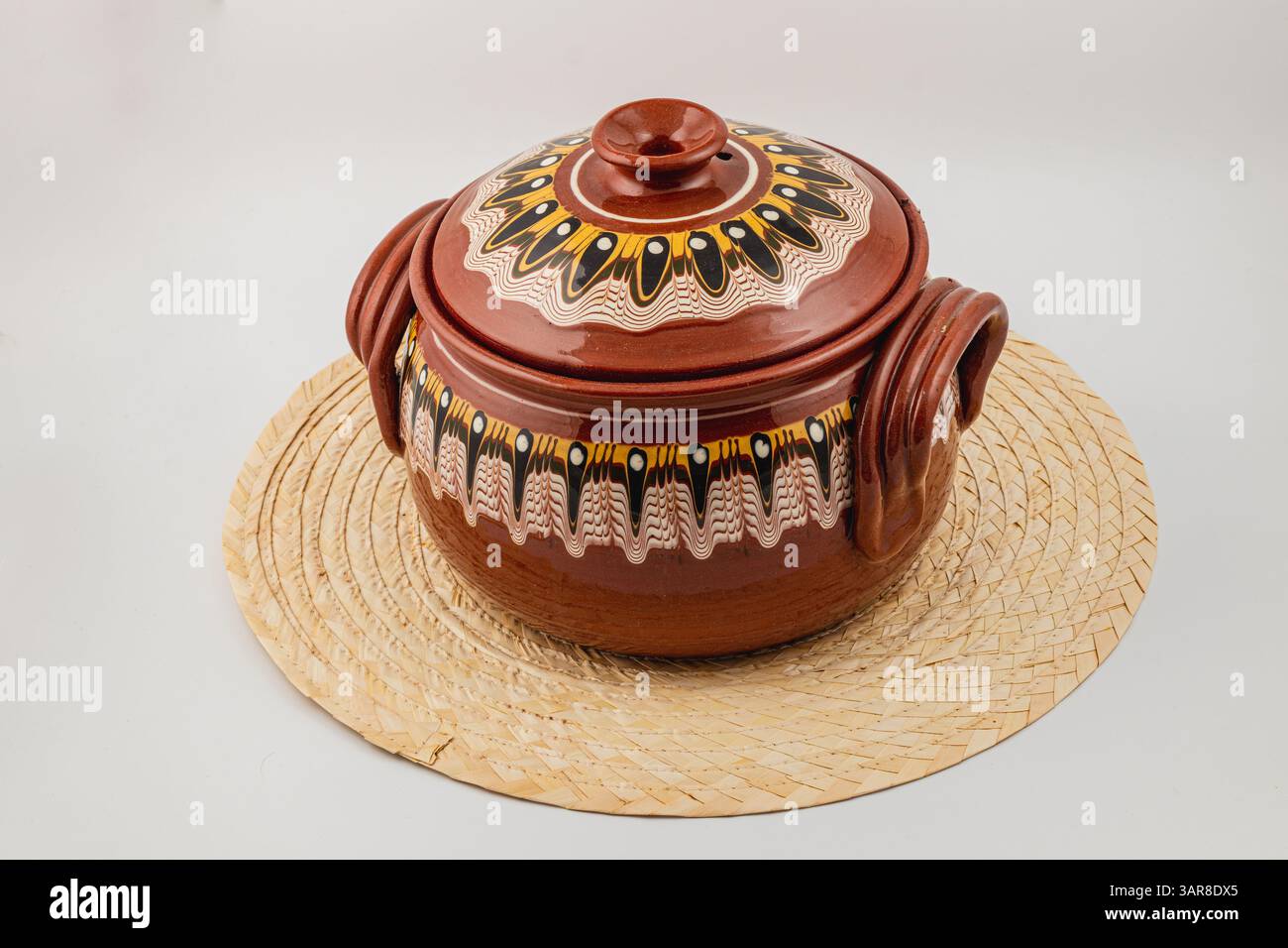 Traditional clay pot featuring detailed designs is displayed on a woven ...