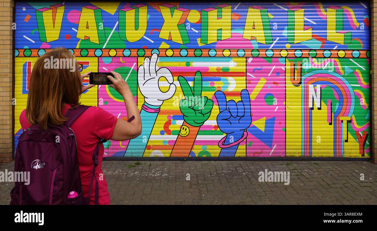 Woman using smartphone to photograph colourful graffiti on a shop ...