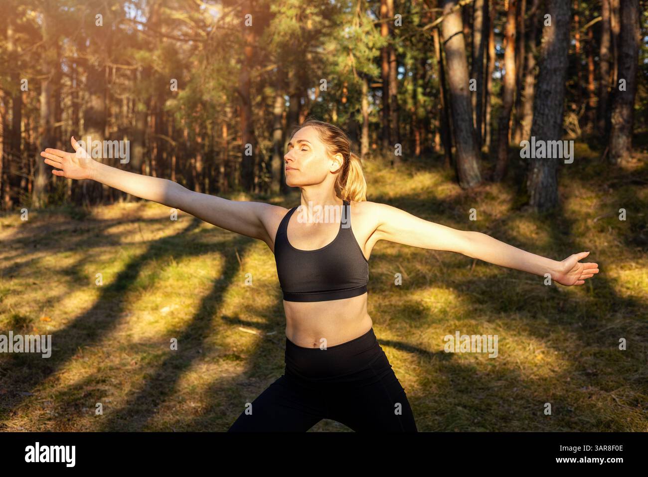 woman doing pilates workout in a sunny forest. enjoying the beauty of ...