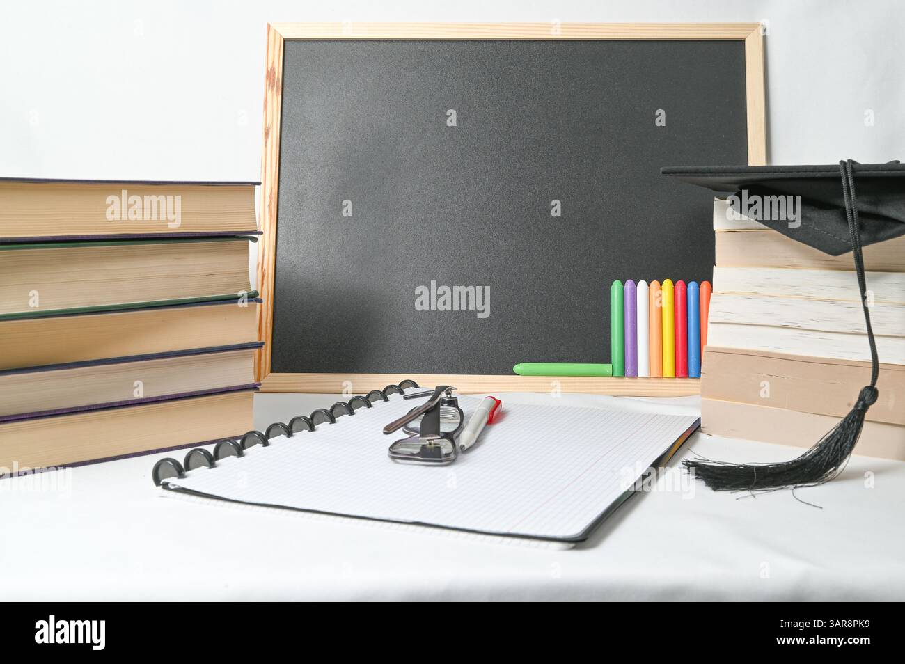 A graduation cap is placed next to a large chalkboard and an open ...