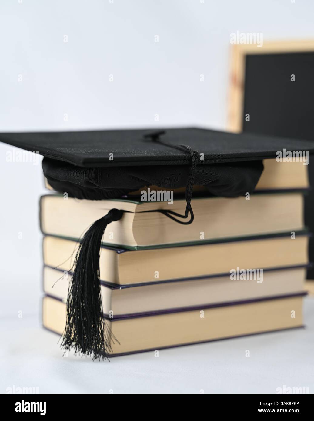 A traditional graduation cap is carefully placed atop a large stack of ...