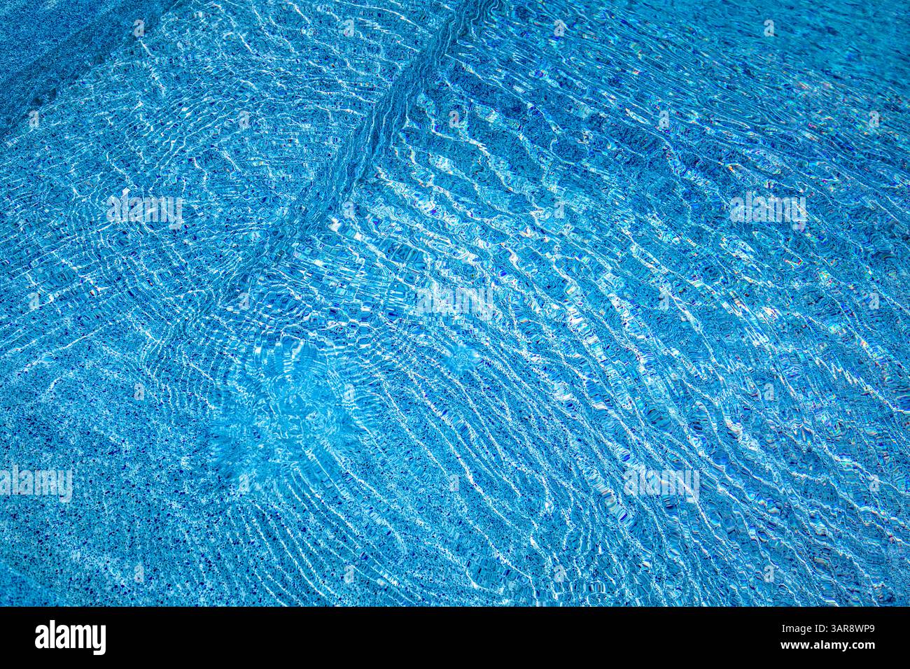 Closeup view of abstract swimming pool water with rippling summer light ...