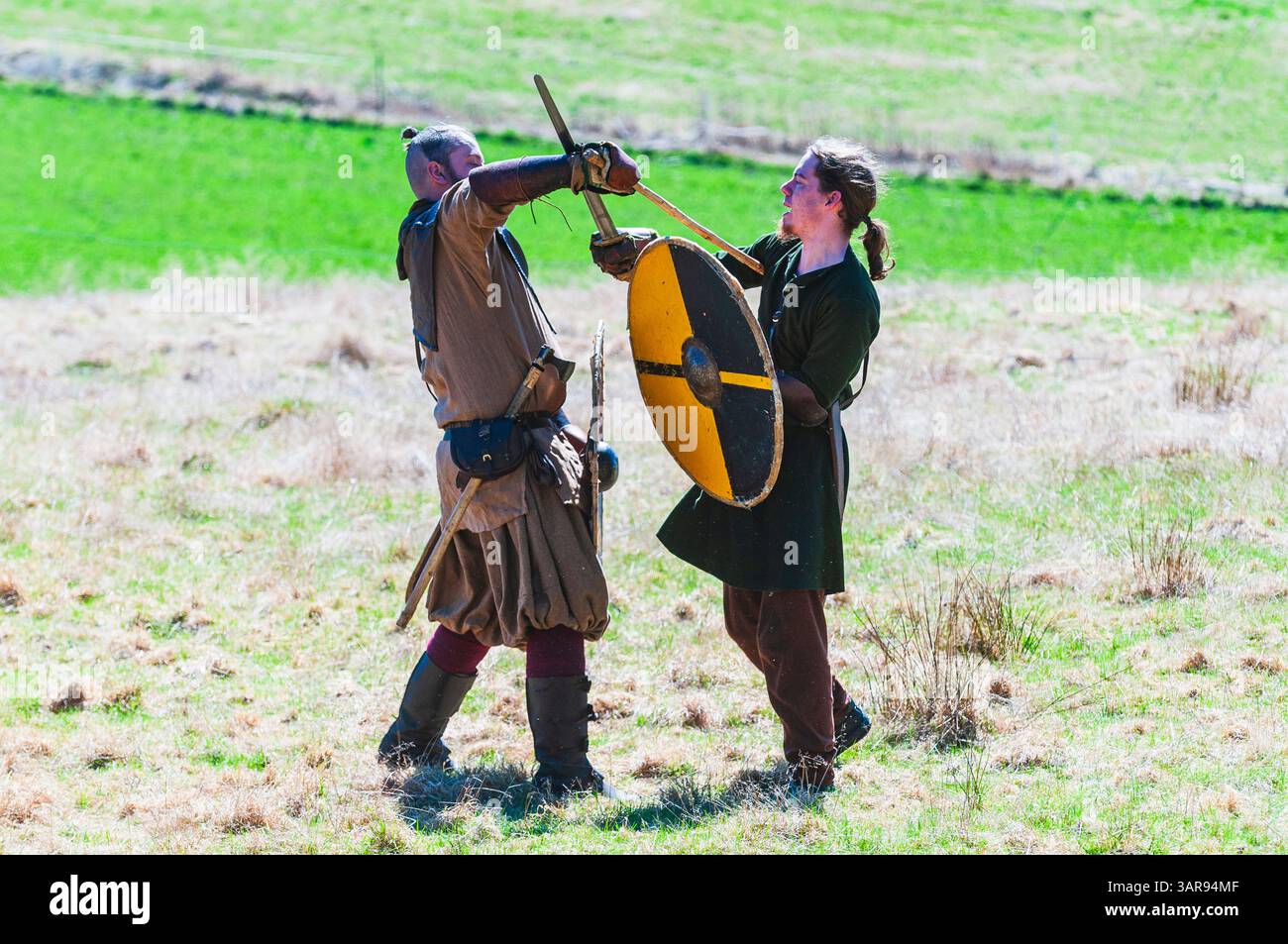 Two Vikings clash with swords and shields in a rural field in Sweden ...