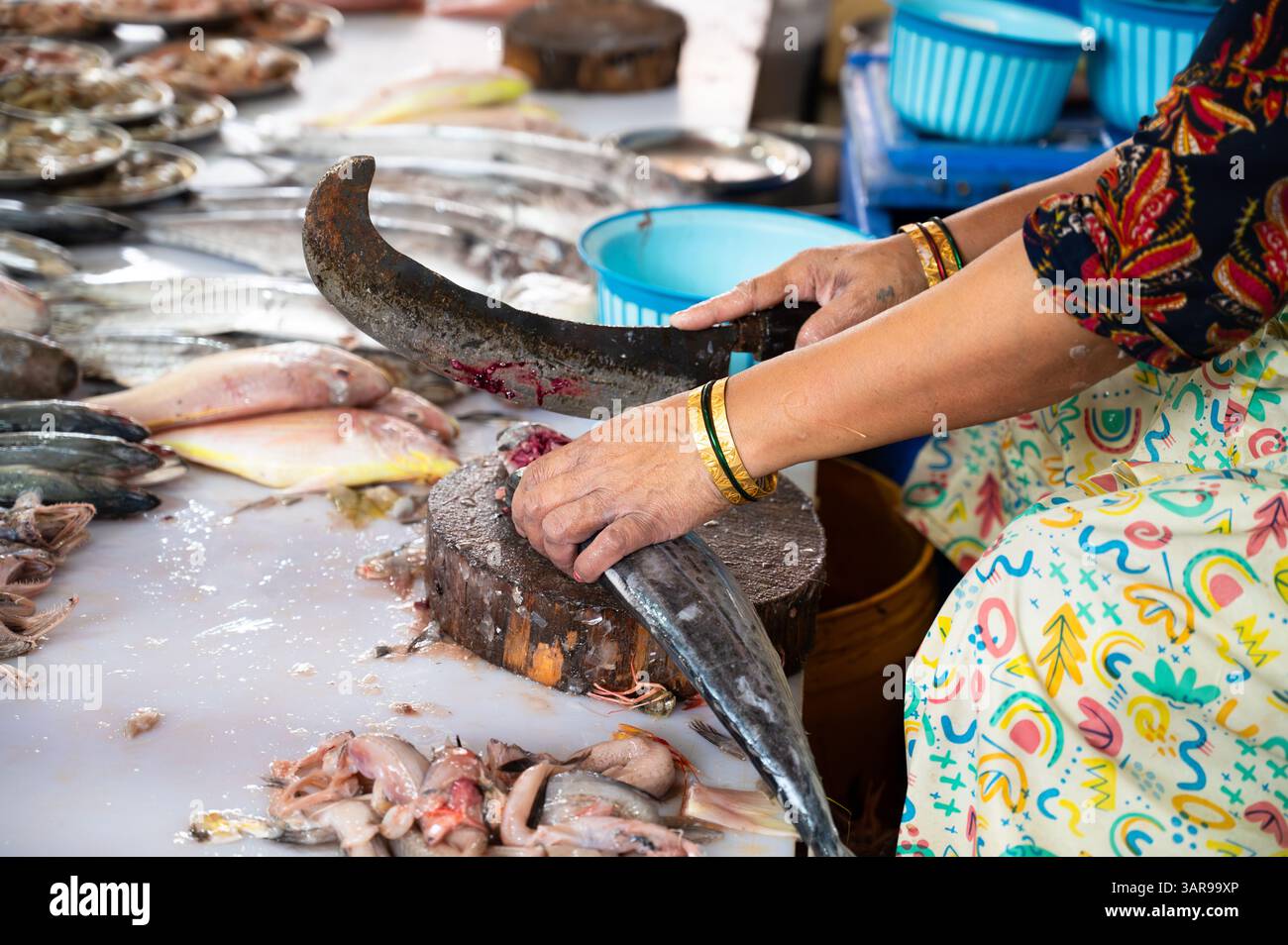 Indian woman cutting fish on a market in Mumbai India, sales stall with ...