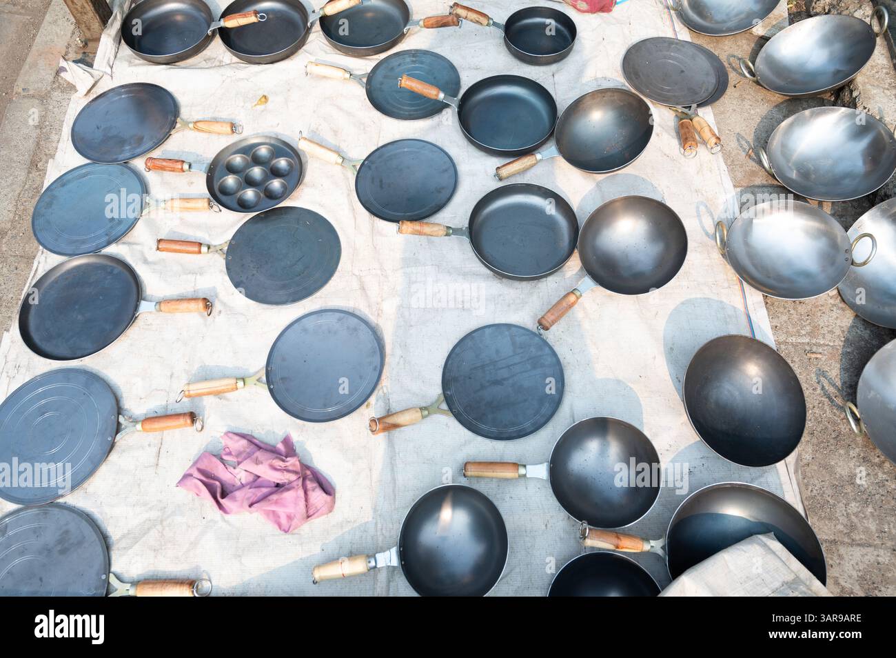 Indian cooking pots and pans sold on a market stall on the street in India, iron kitchen ...