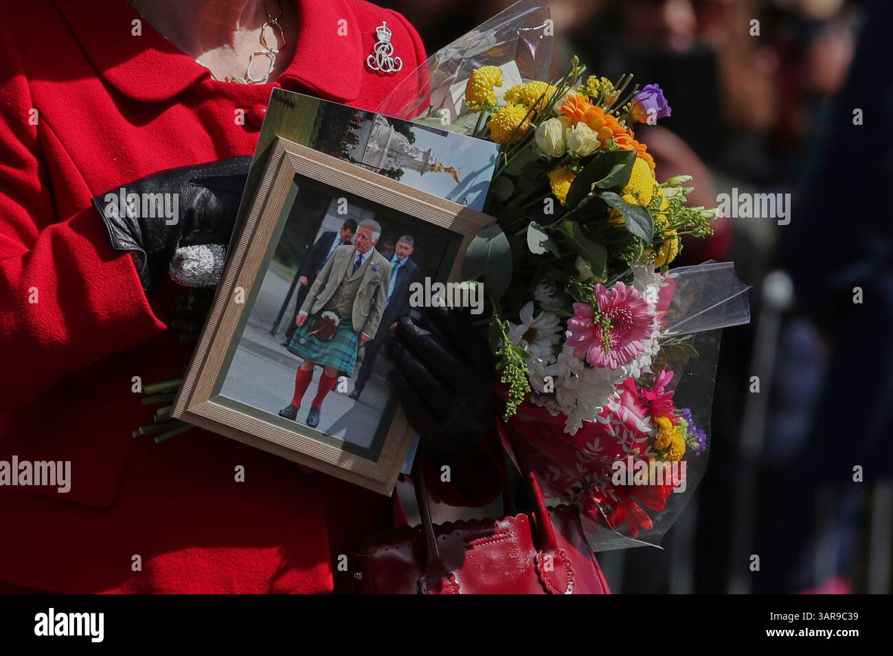 A royal aide hold gifts and flowers given to Britain's King Charles III ...