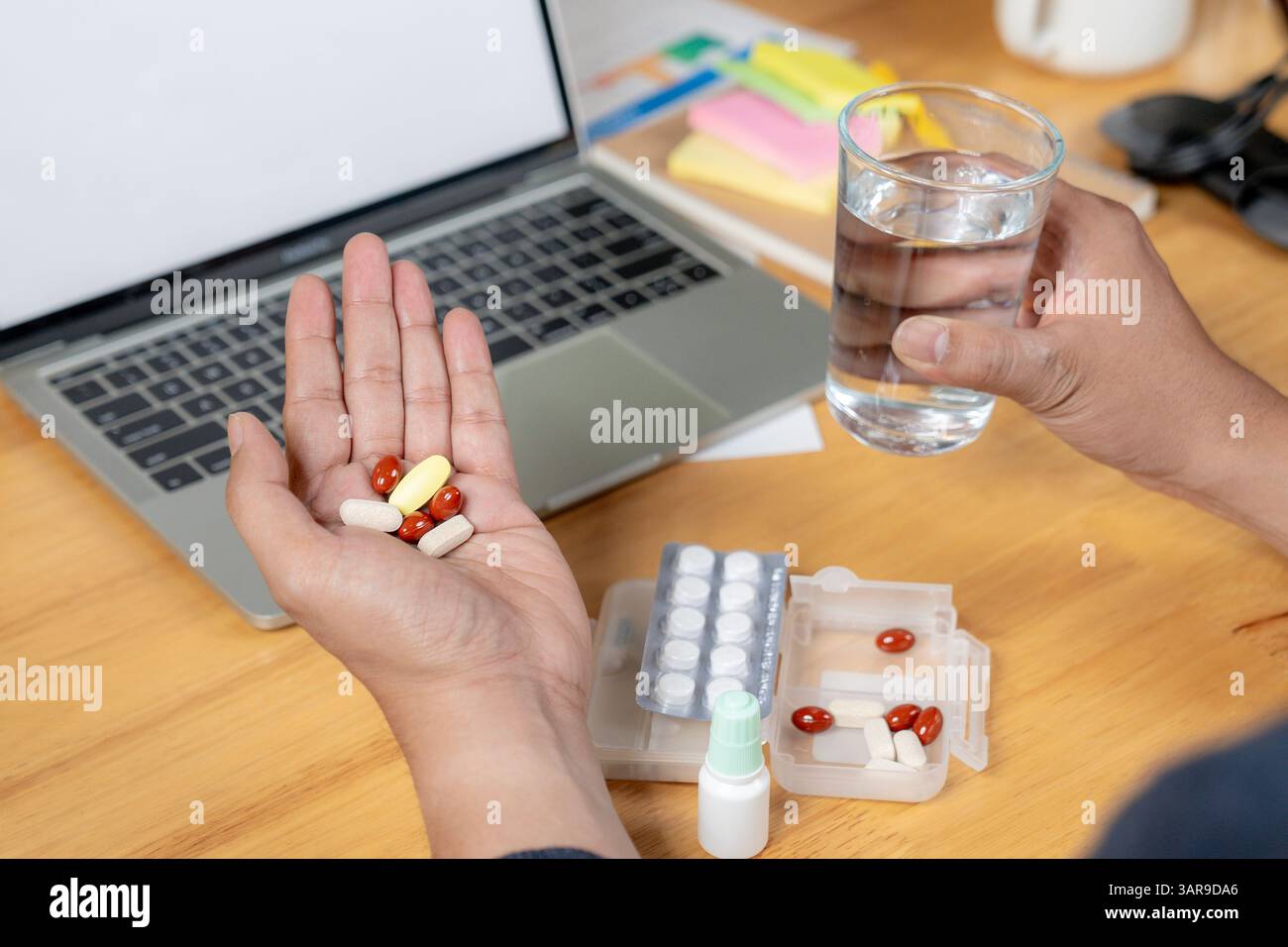 Rear view of a businessman taking pain relief medication after long ...