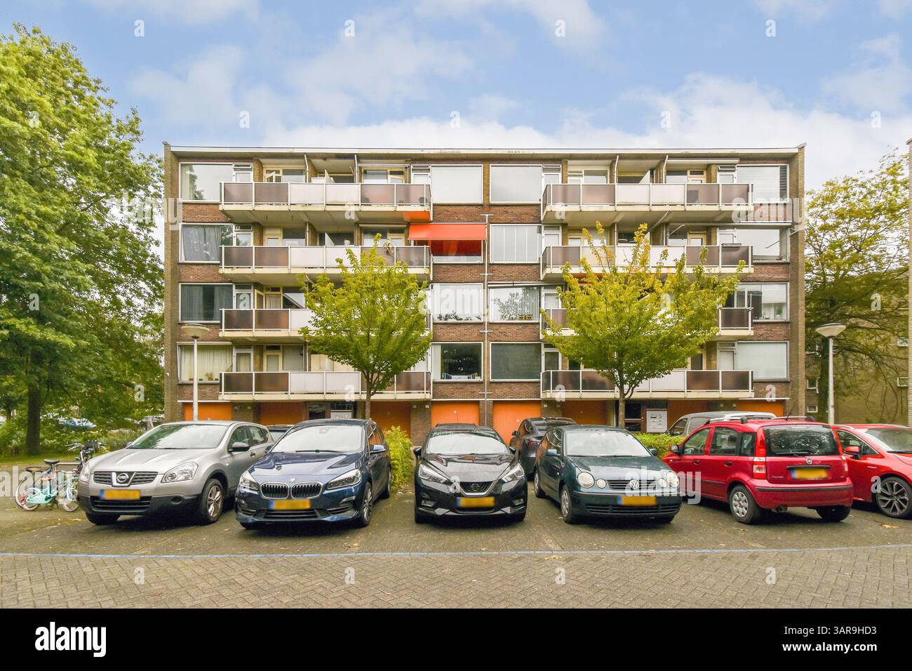 A multi-story apartment building featuring a parking area with various ...