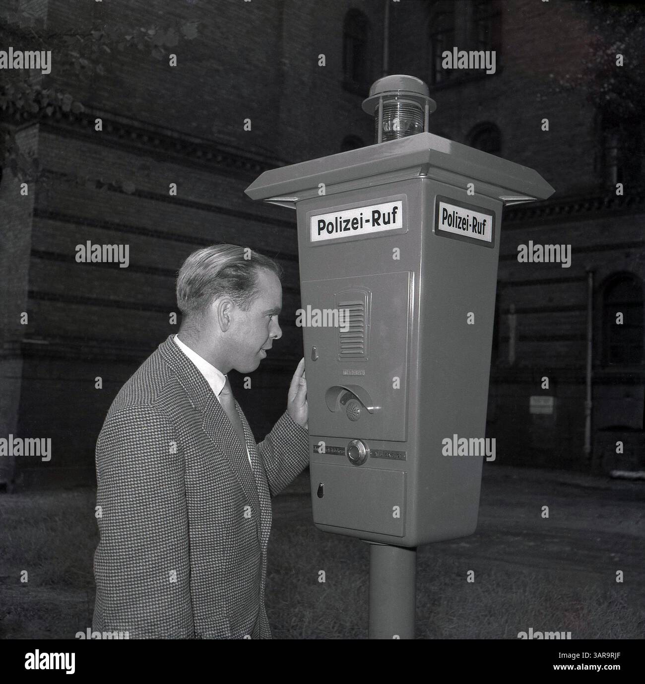 Late 1950s, historical, a man using a new police call/voice box ...